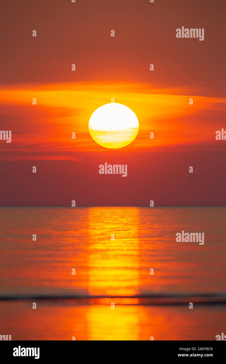 Sun setting into sea Stock Photo - Alamy