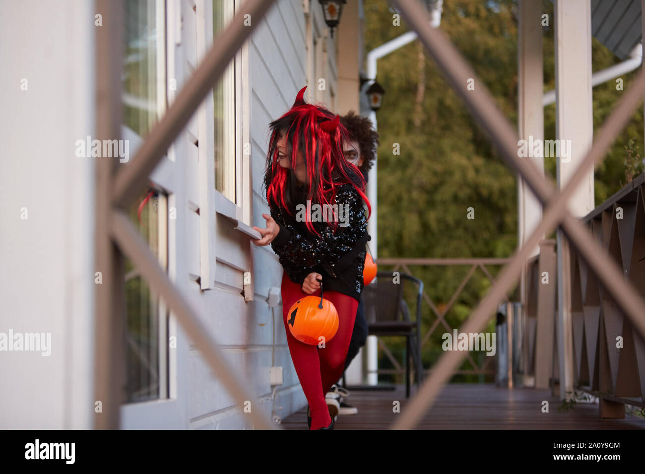 Portrait of two sneaky children hiding outside house while playing ...