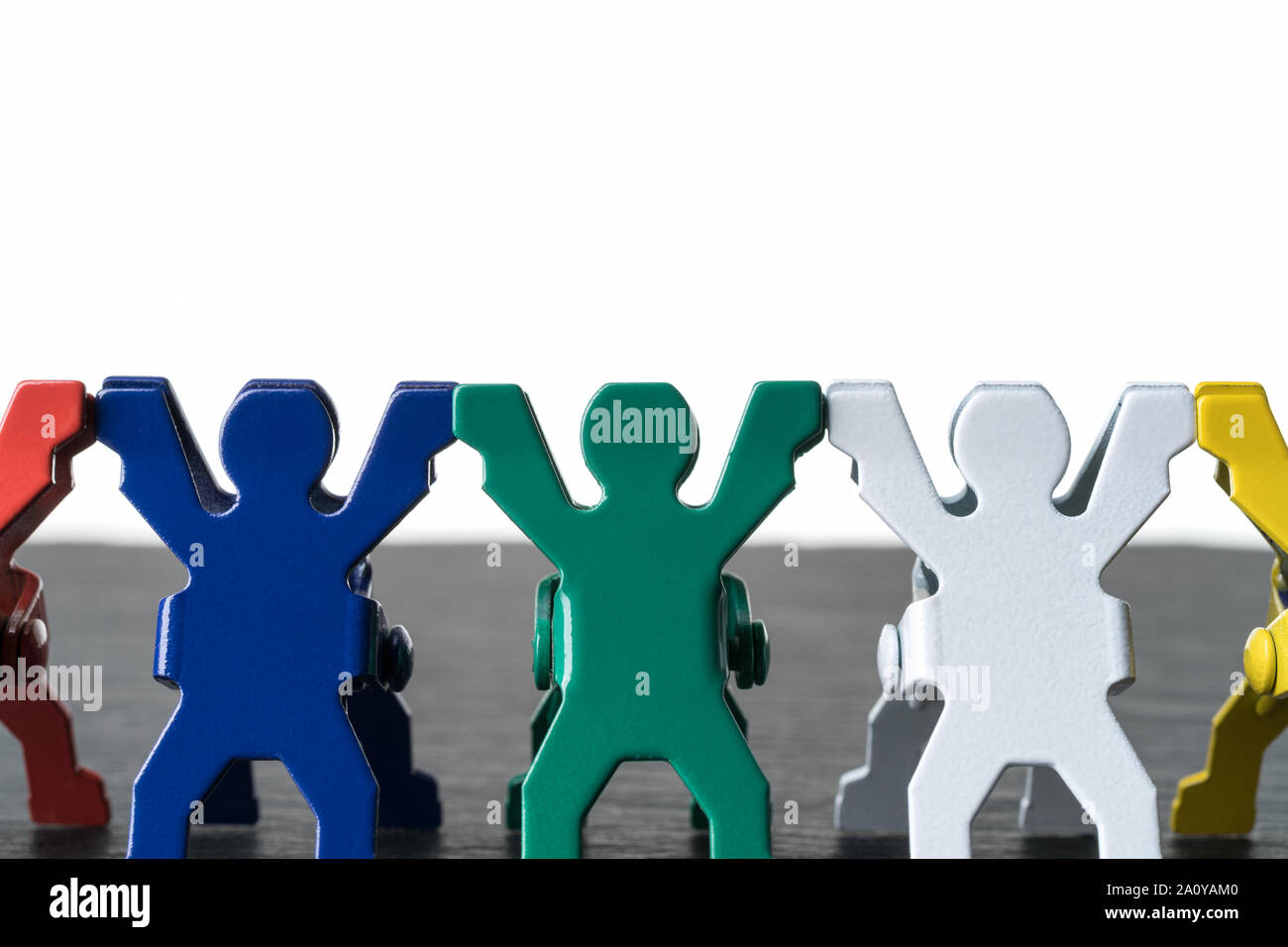 Colorful diverse miniature people figurines standing in a row on a dark ...