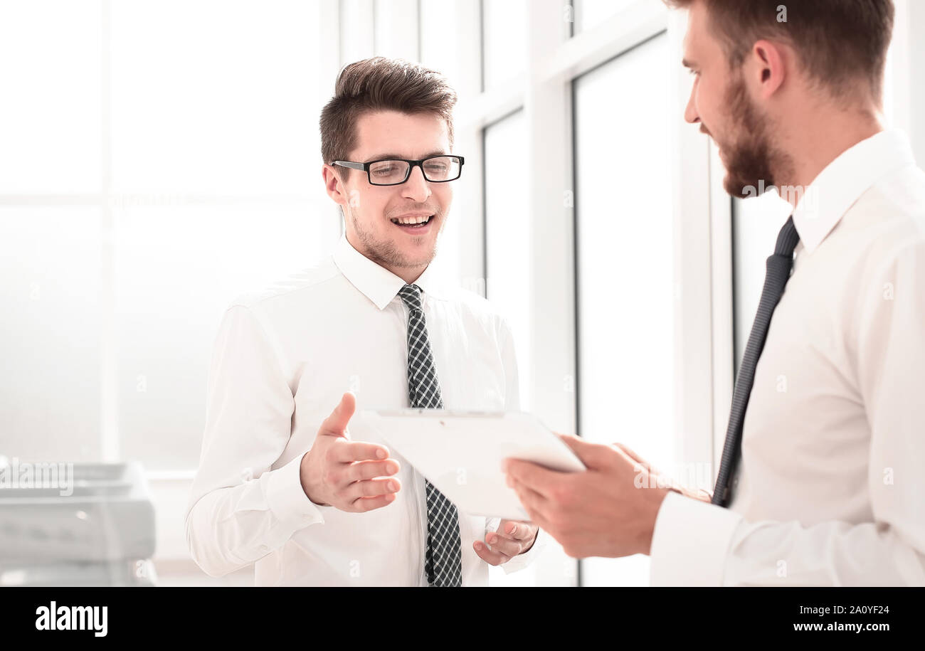 two employees with a digital tablet discussing something standing in ...