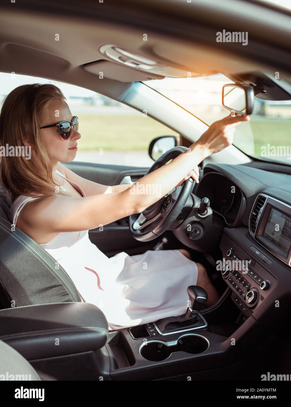 Girl woman in car in summer city, looks in rearview mirror, parking car ...