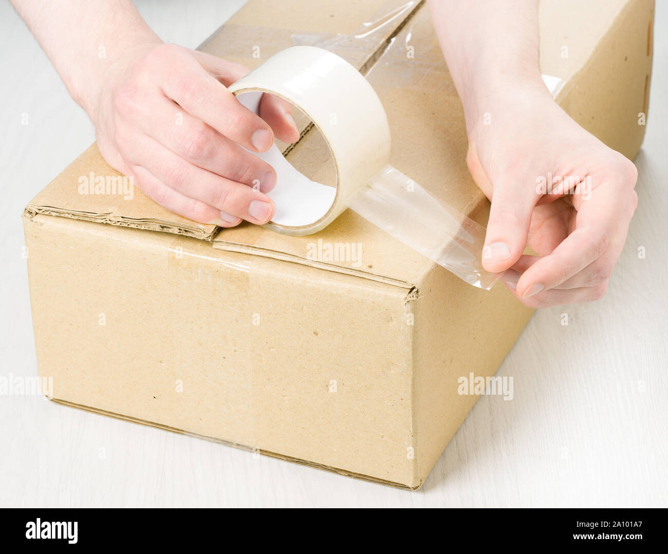 Hands with roll adhesive tape on a cardbox Stock Photo - Alamy