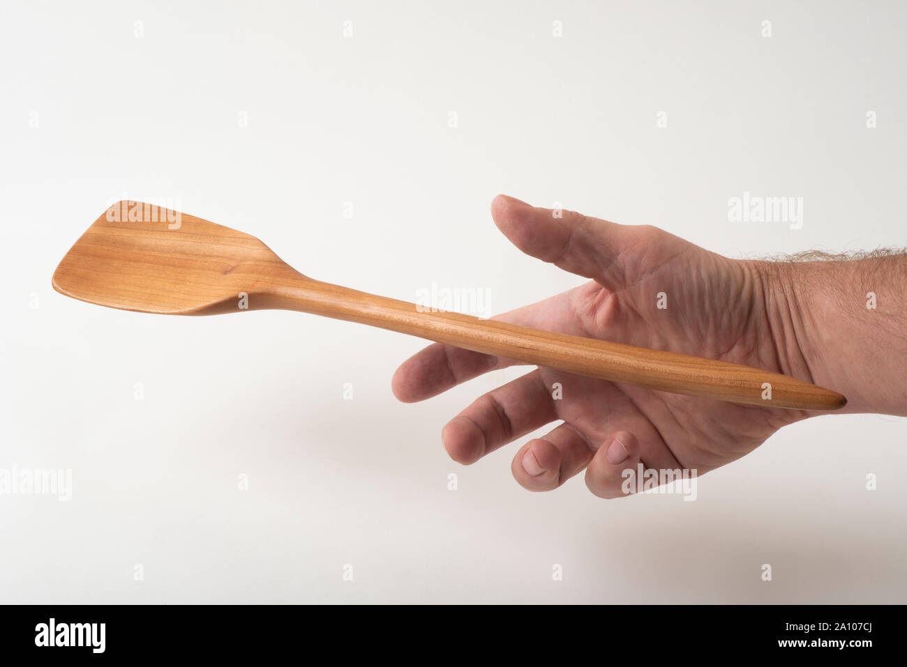 Male hand shown reaching for a handmade wooden spatula from cherry wood ...