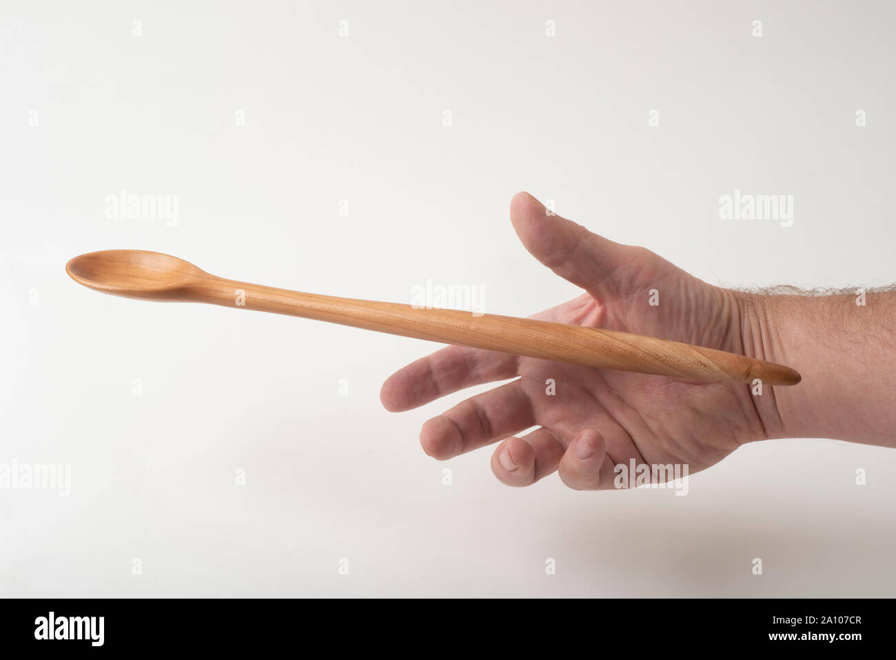 Male hand shown reaching for a handmade wooden spoon from cherry wood ...