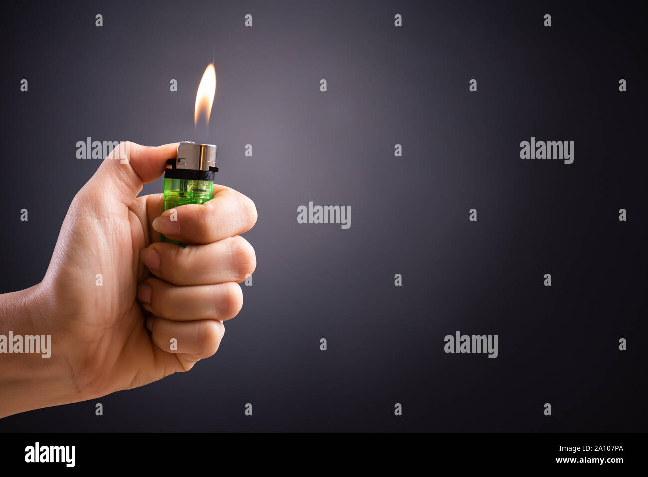 Close up woman hand holding a burning lighter in the dark background ...