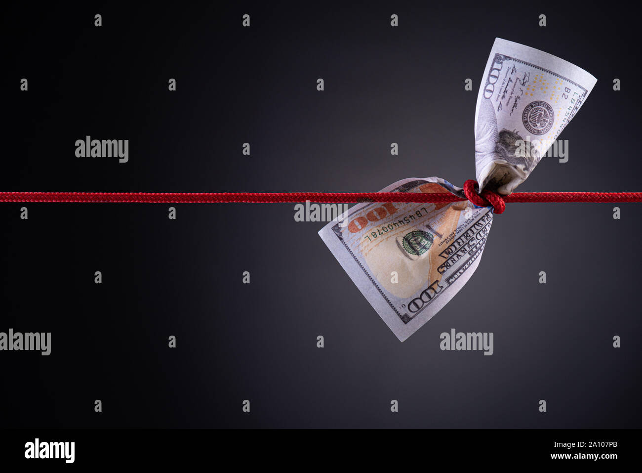 American dollar tied up in red rope knot on dark background with copy ...