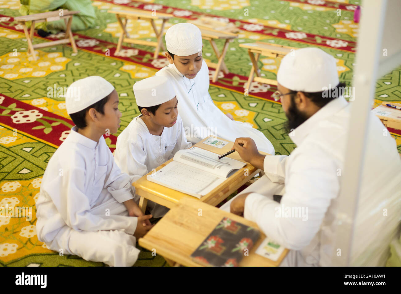An adult religion teacher teaching children studying inside Masjid ...