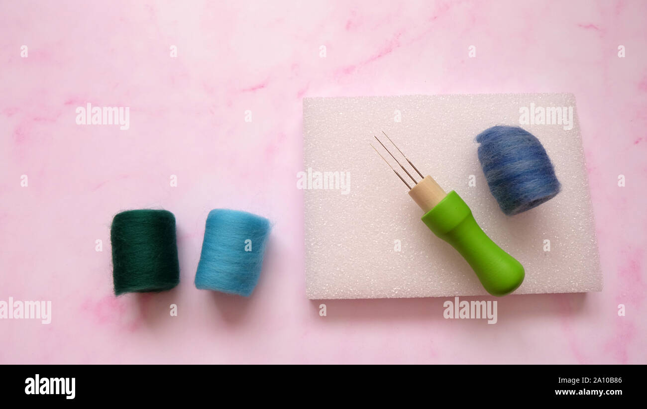 Flat lay of blue felt wool rolls and felting kit of felt needle and ...