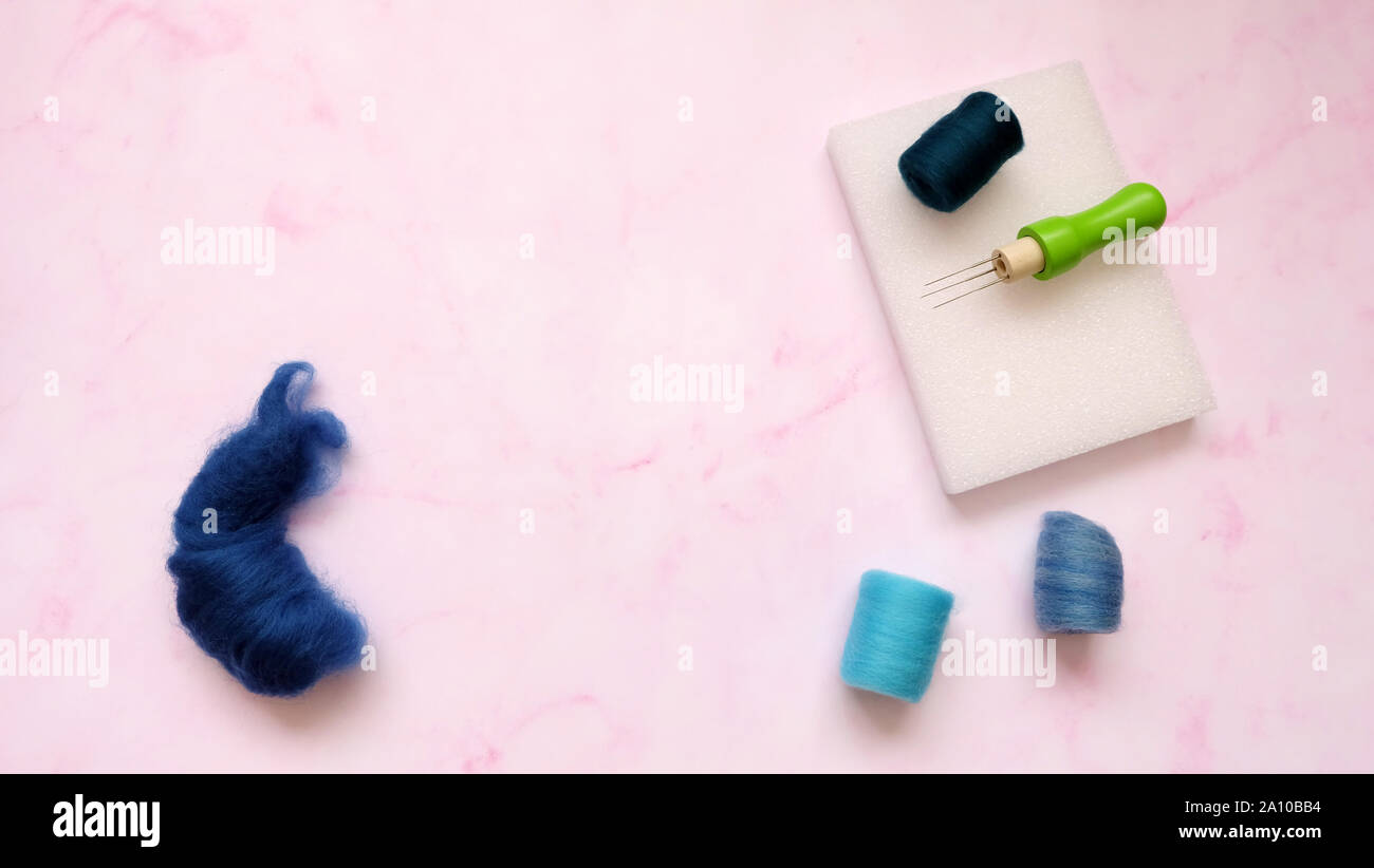 Flat lay of blue felt wool rolls and felting kit of felt needle and ...