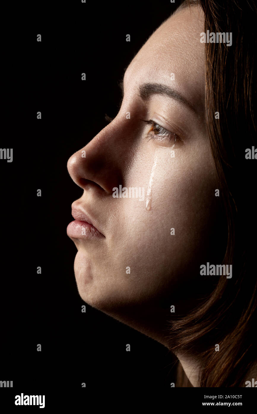 sad woman crying, looking aside on black background, closeup portrait ...