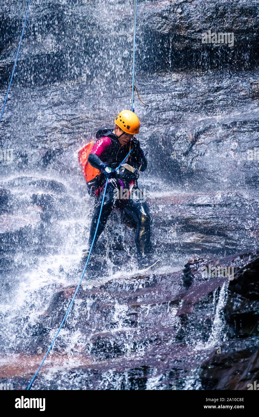 Blue Mountains, Australia - Sept 7 2019: Man getting wet rappelling ...