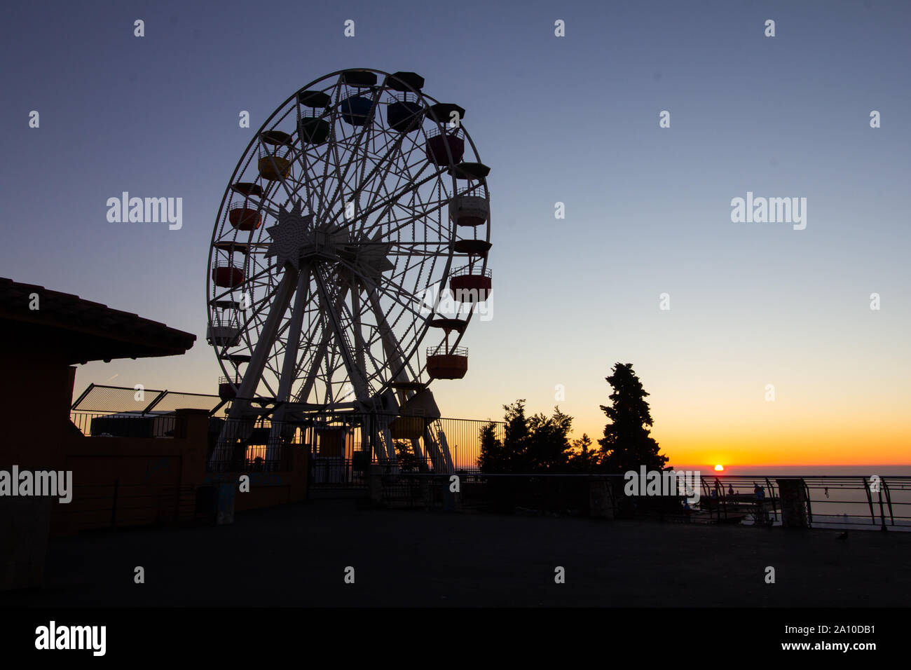 The Ferris whell at Tibidabo amusement park in silhouette at sunrise ...
