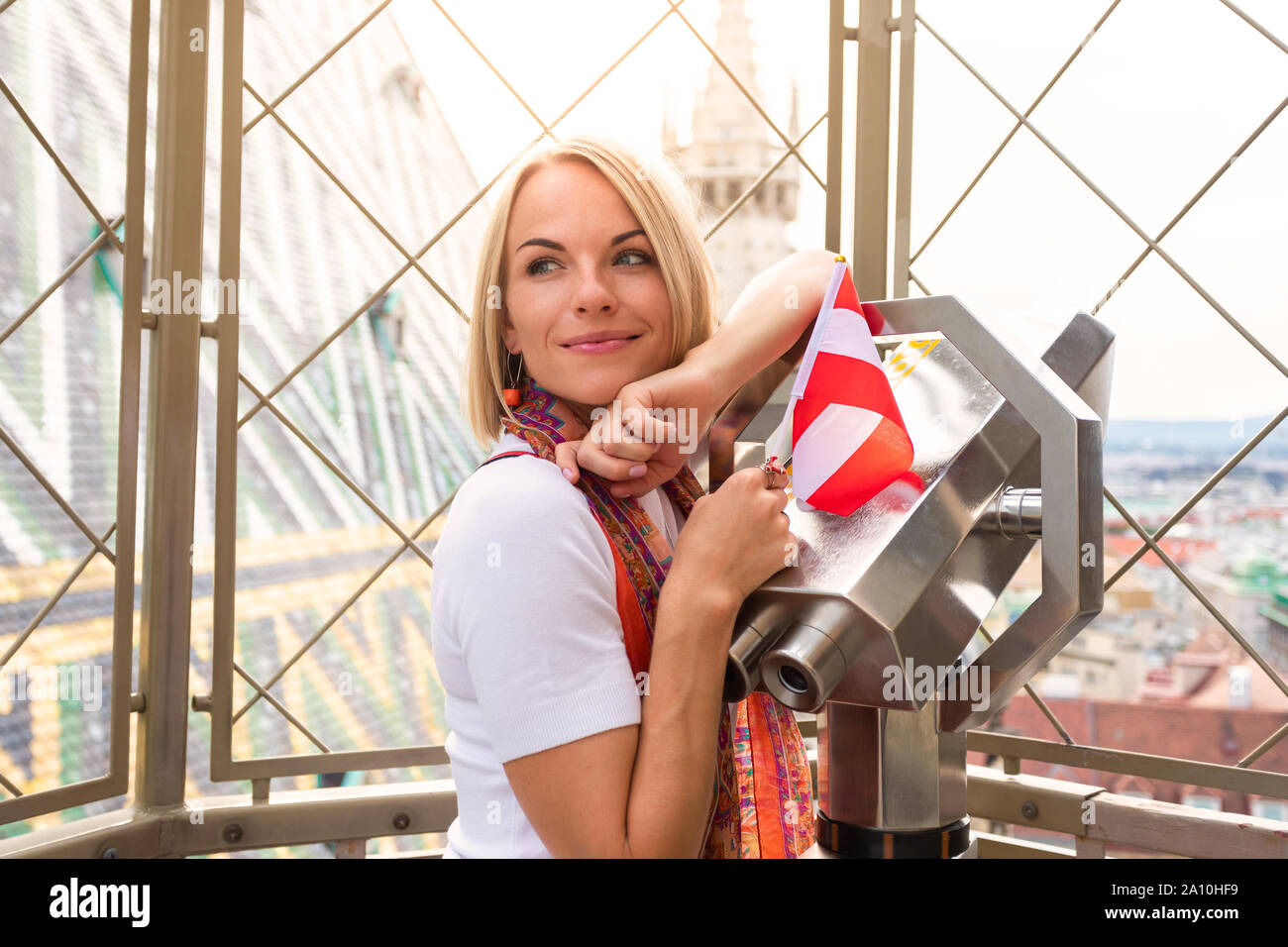 A young woman with the flag of Austria in her hands looks through ...