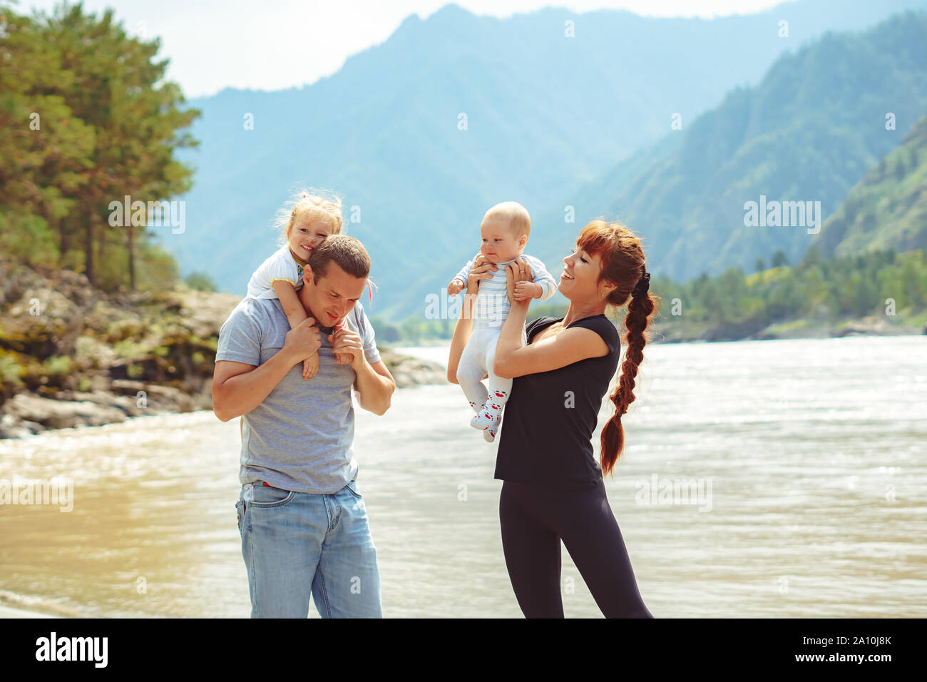 family with two children on the river Bank against the mountains Stock ...