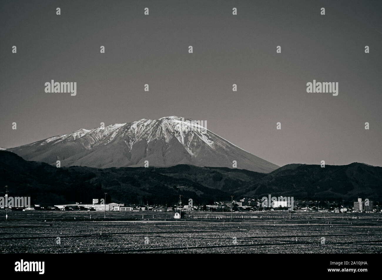 Snow covered Mount Akita Komagatake and local town along train route ...
