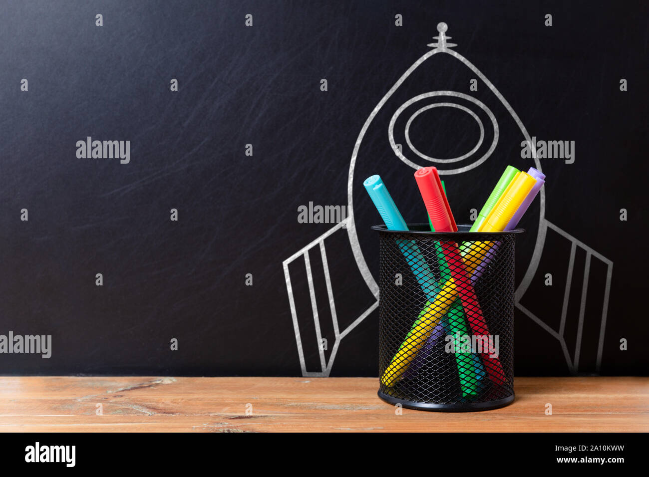School stationery supplies and hand drawn rocket ship on dark ...