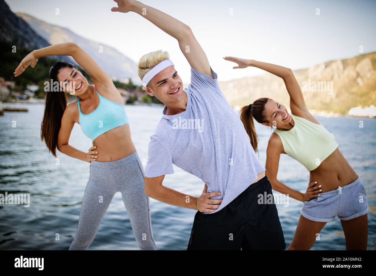 Fit group of happy people exercising outdoor. Smiling friends doing ...