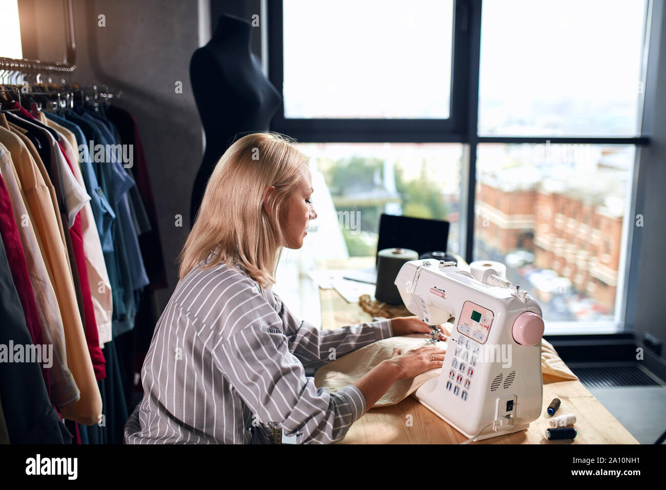 sewing service concept. seamstress working in a small ndependent shop ...