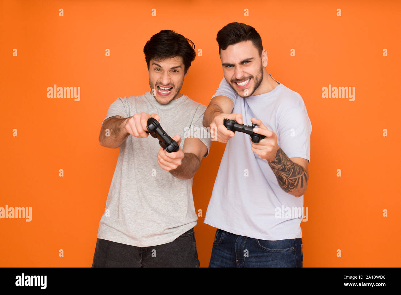 Gamers. Two mates playing video games, orange background Stock Photo ...