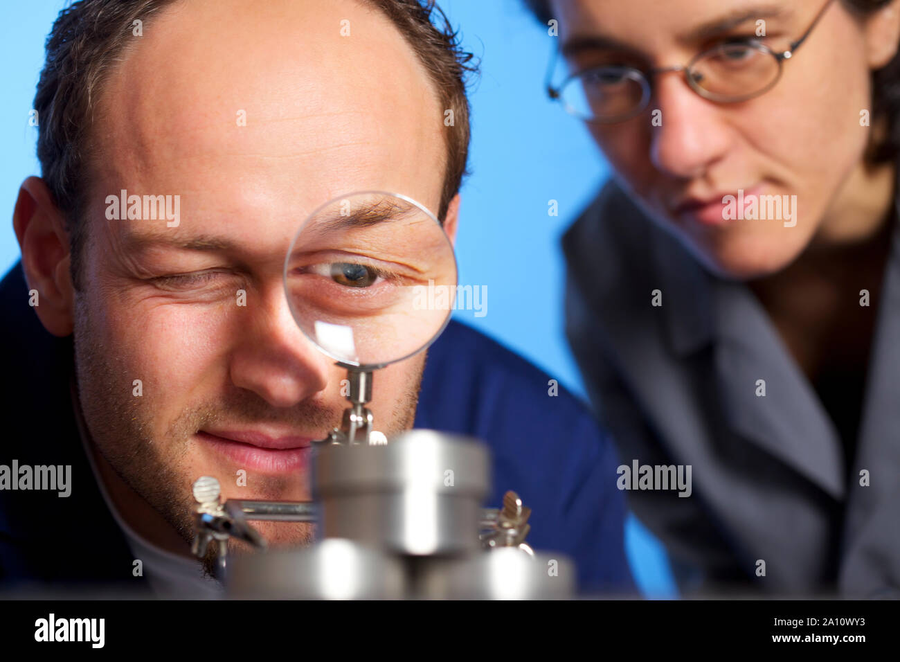 Engineer inspecting parts through magnifying glass Stock Photo - Alamy