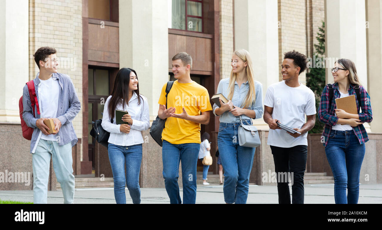 Multiracial students walking against university building during break ...