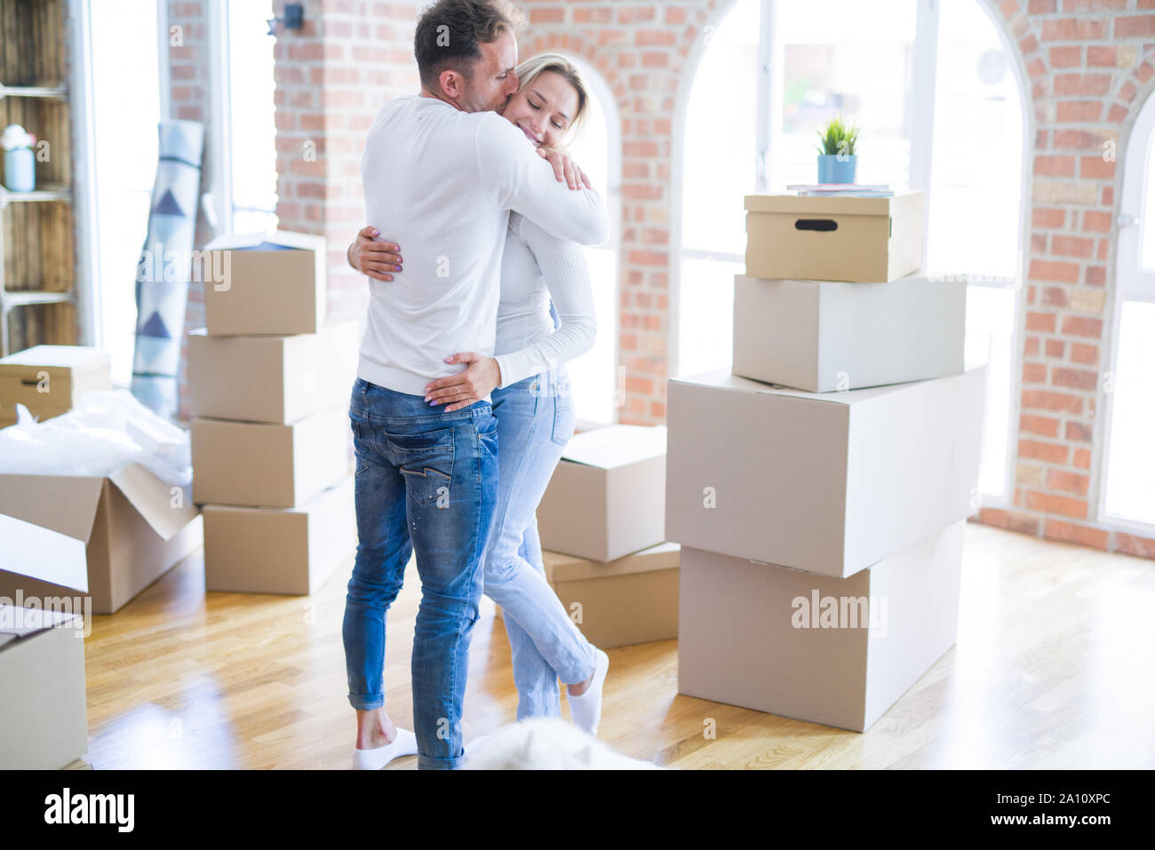 Young beautiful couple hugging at new home around cardboard boxes Stock ...