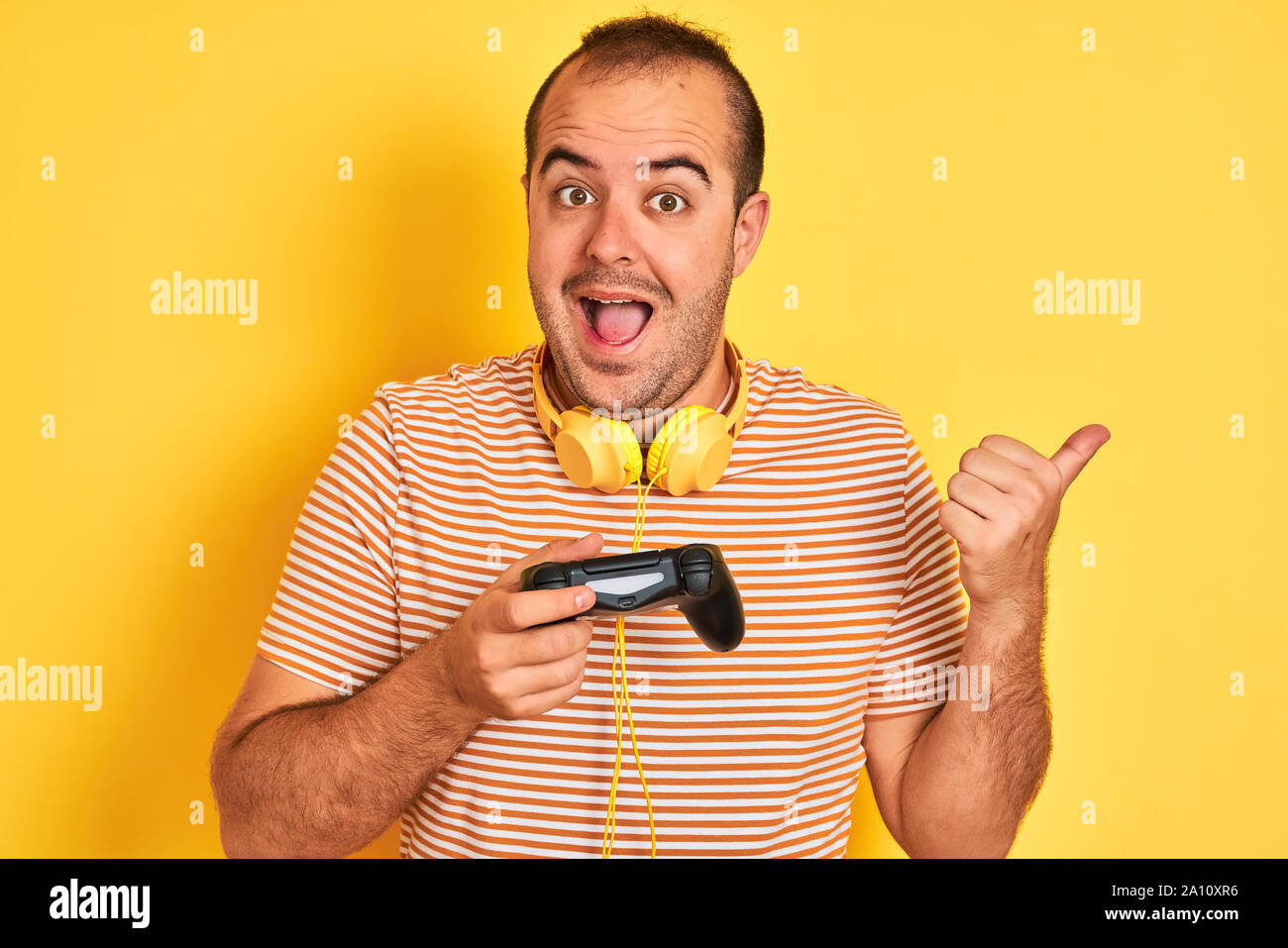 Young gamer man playing video game using headphones over isolated ...