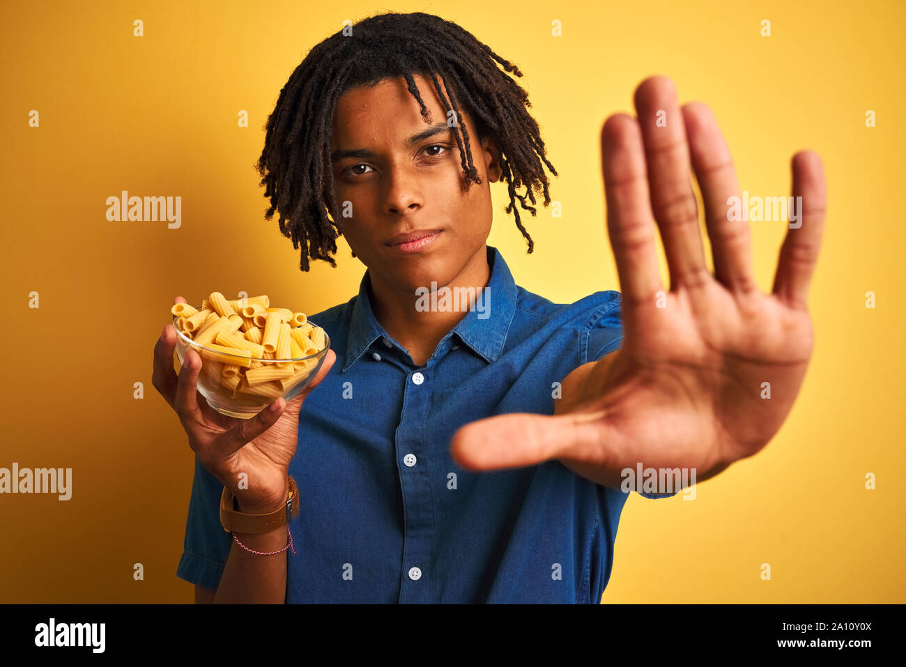 Afro american man with dreadlocks holding pasta macaroni over isolated ...