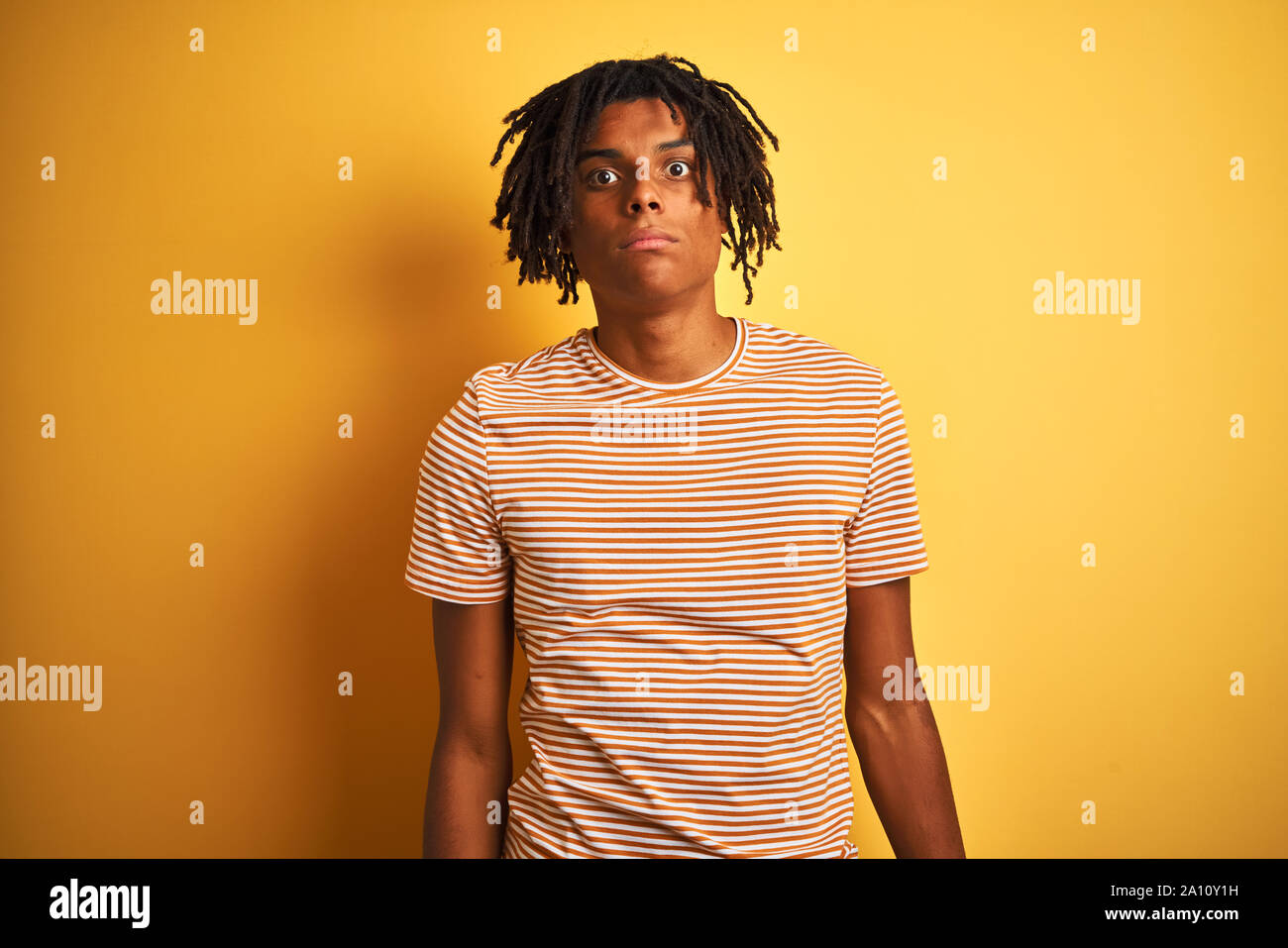 Afro man with dreadlocks wearing striped t-shirt standing over isolated ...
