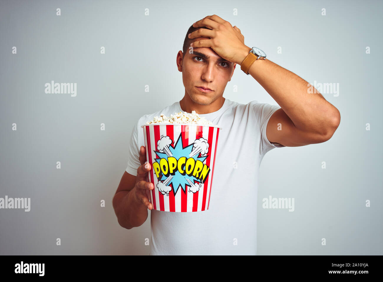 Young handsome man eating popcorn over white isolated background ...