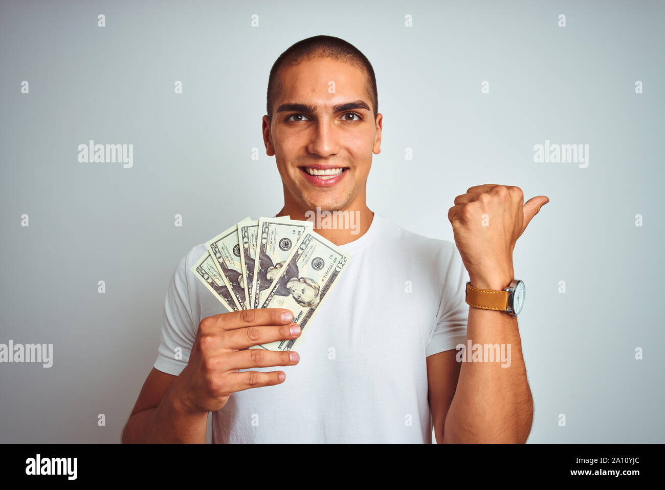 Young handsome man holding dollars over white isolated background ...