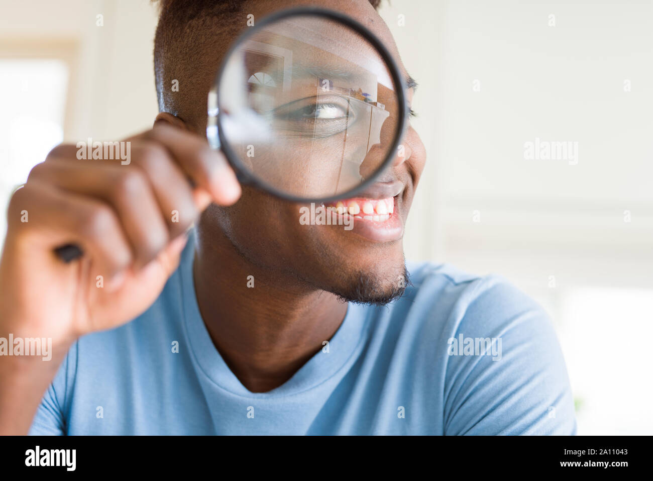 Young african man looking through magnifying glass Stock Photo - Alamy
