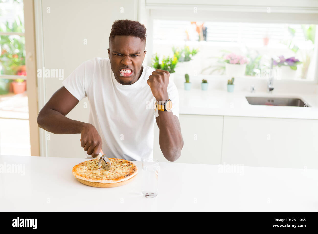 African american man eating cheese pizza at home annoyed and frustrated ...