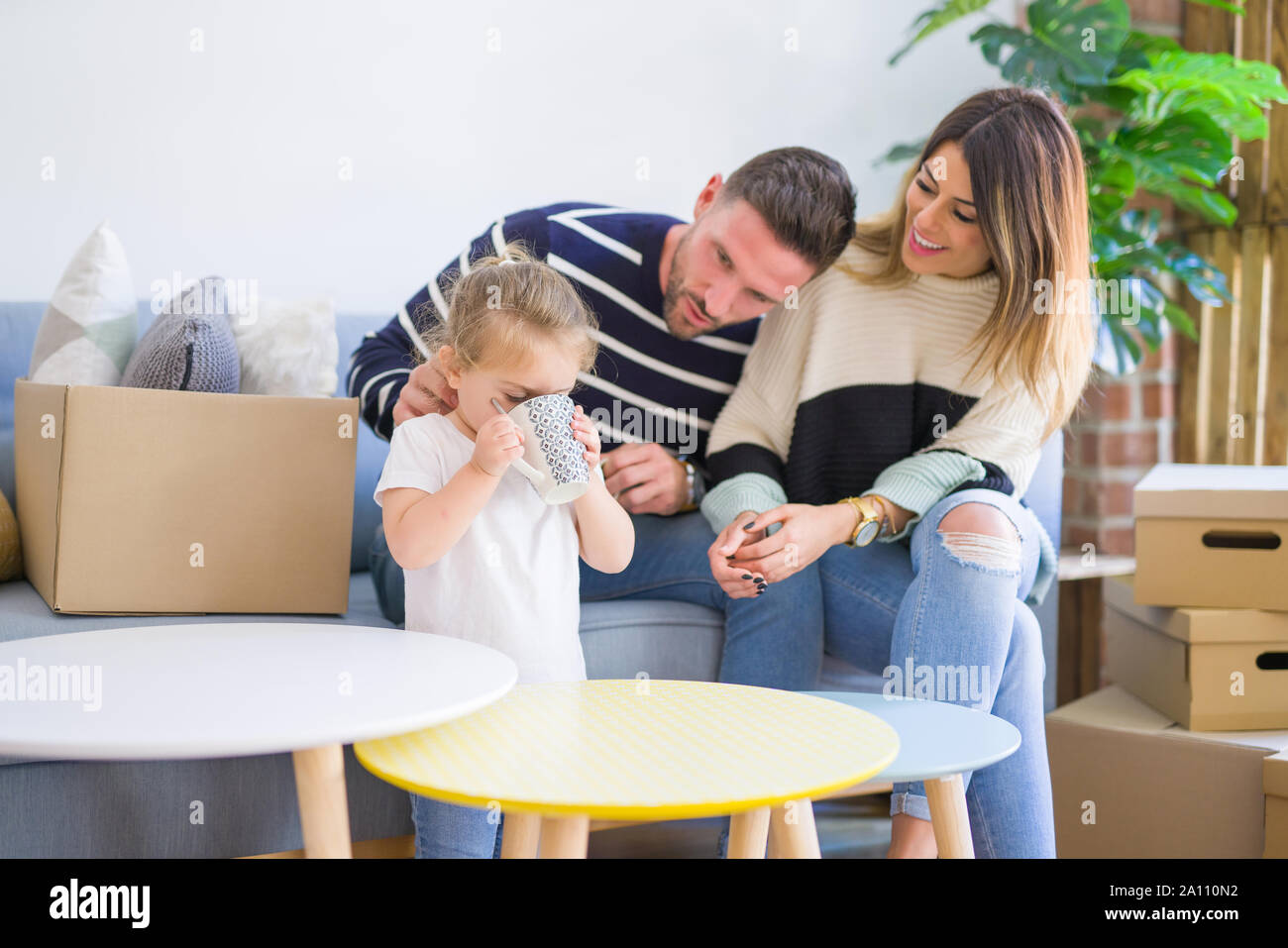 Beautiful family, parents sitting on the sofa drinking coffee looking ...