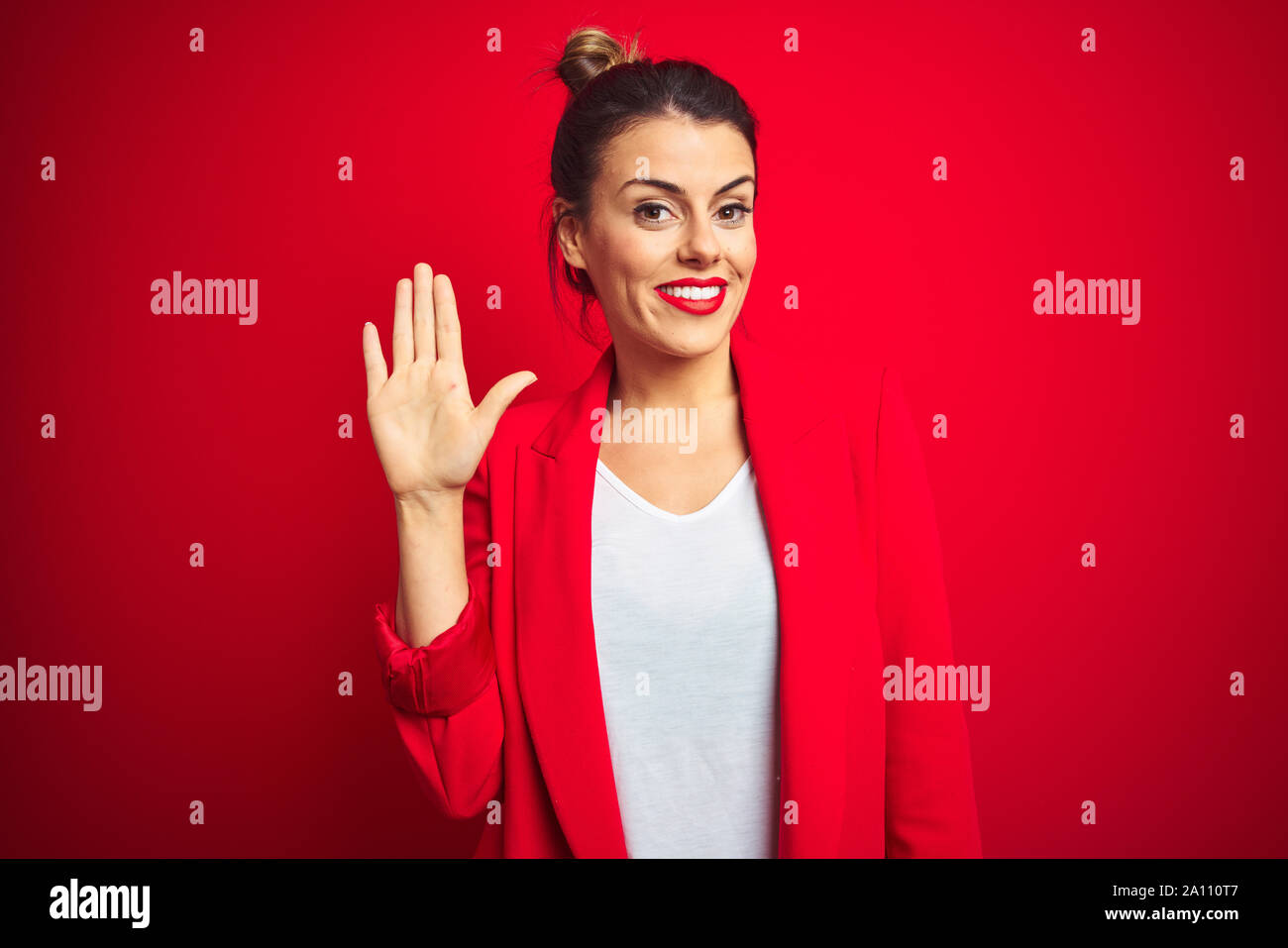 Young beautiful business woman standing over red isolated background ...