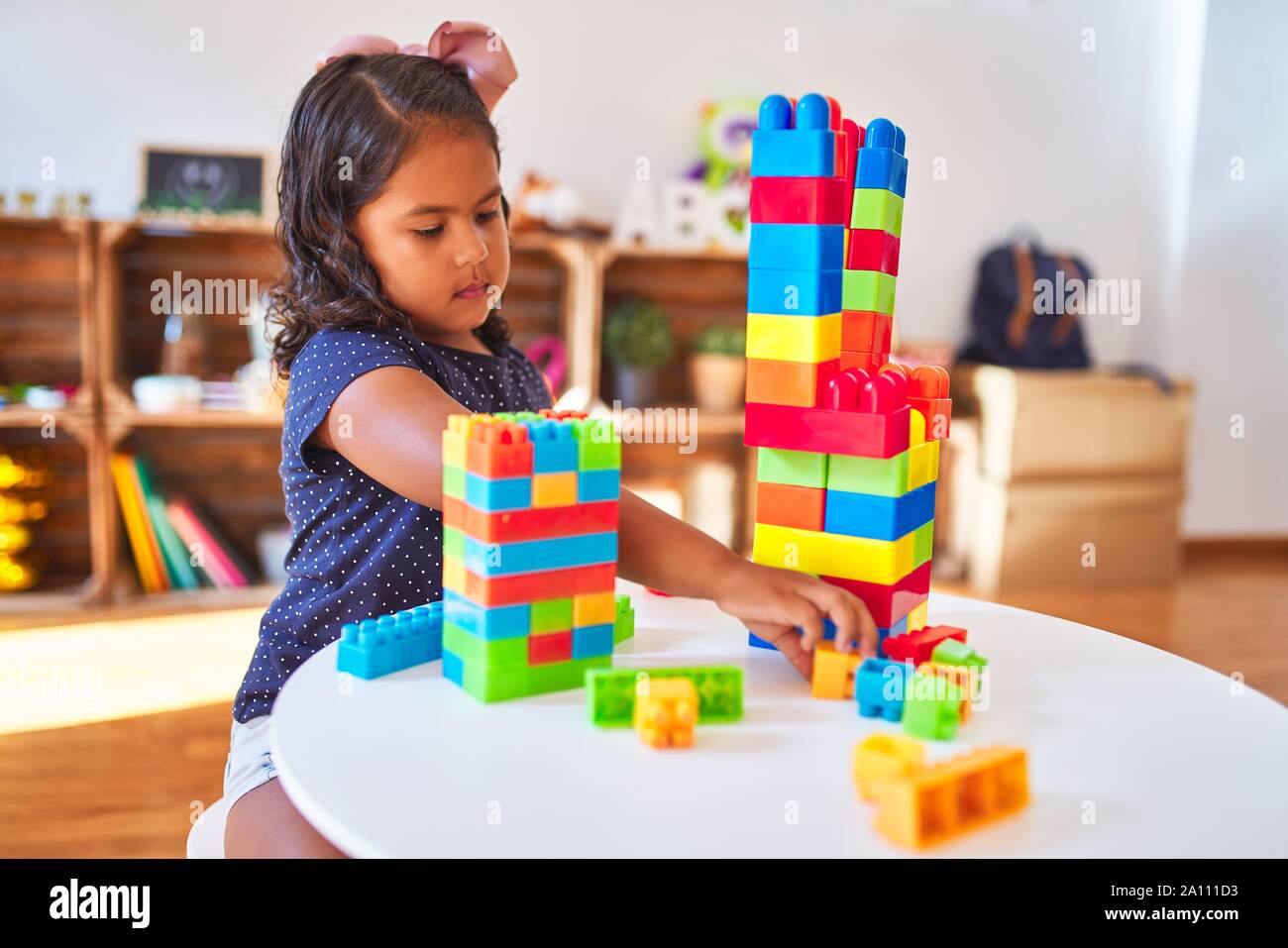 Beautiful toddler girl playing with construction blocks at kindergarten ...