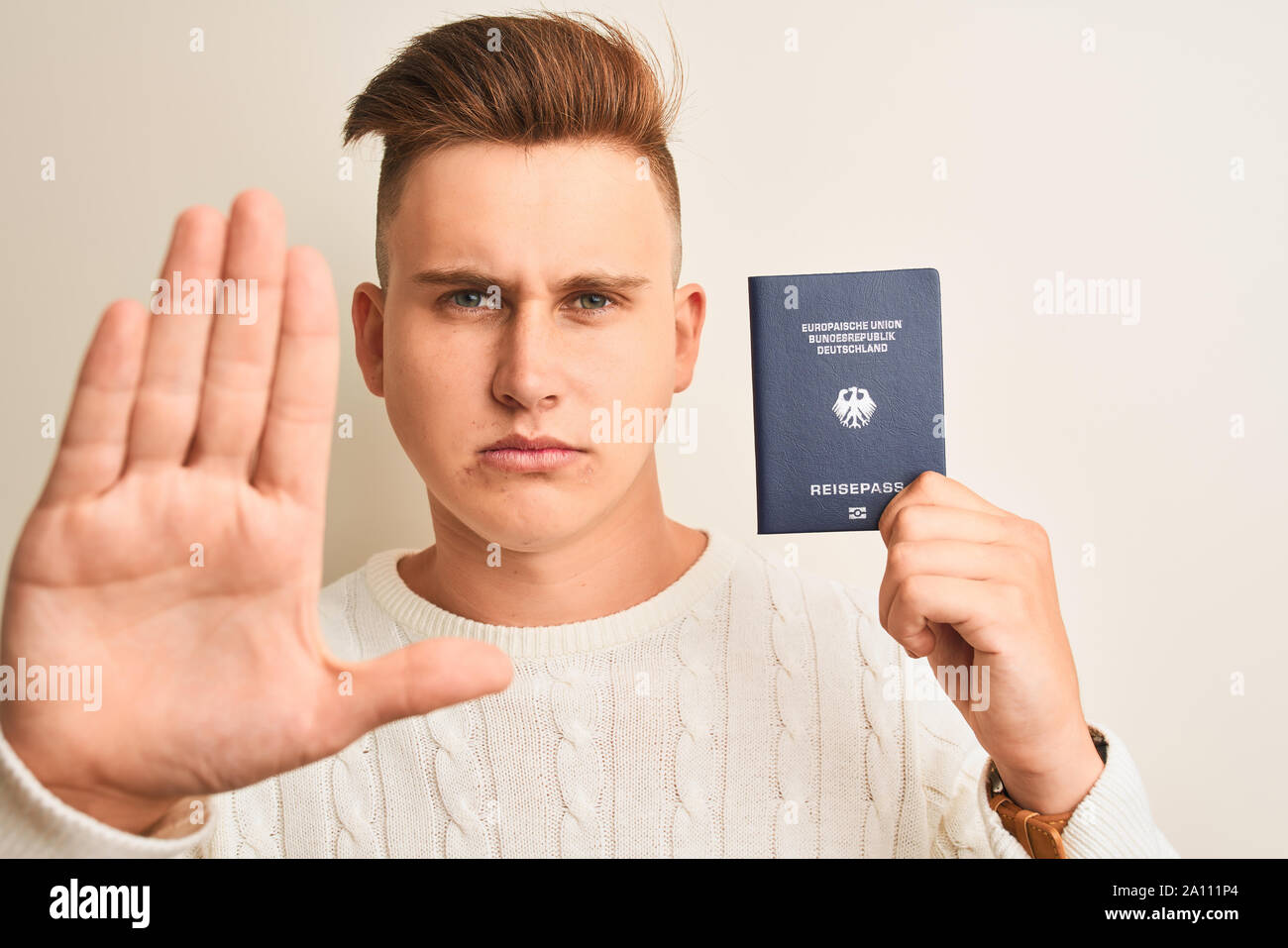 Young handsome man holding Germany German passport over isolated white ...