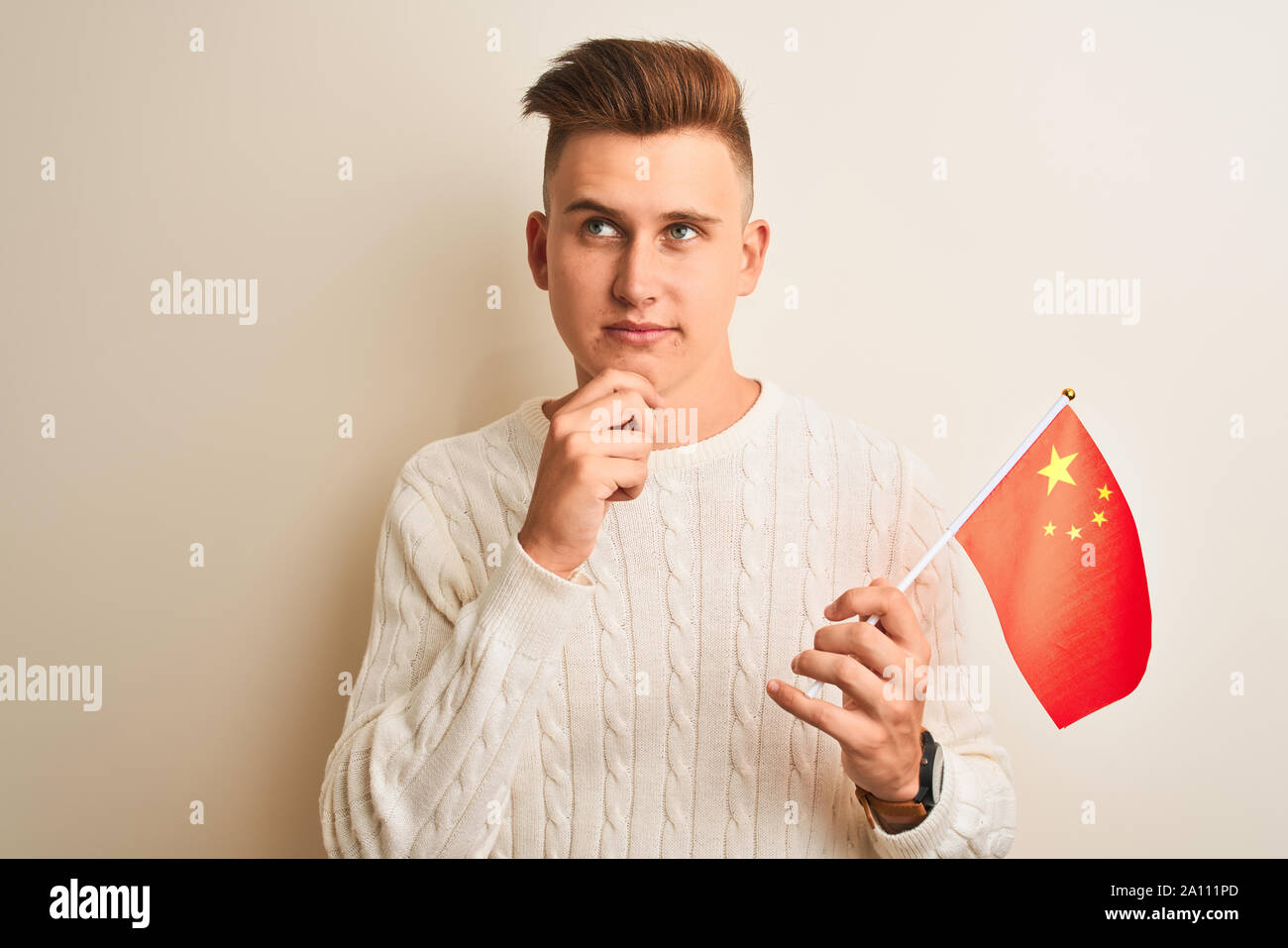 Young handsome man holding Chinese China flag over isolated white ...