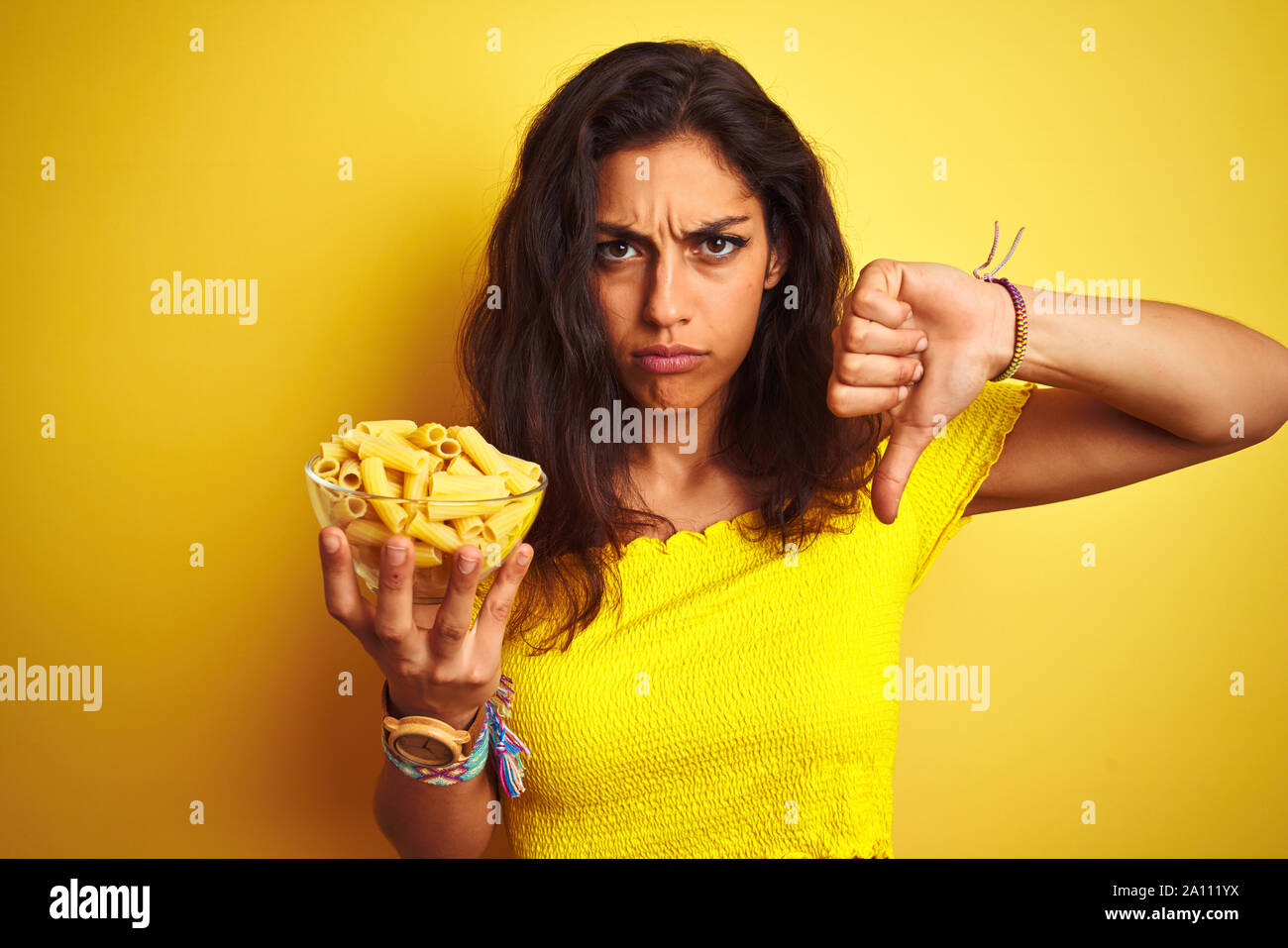 Young beautiful woman holding bowl with dry macaroni pasta over ...