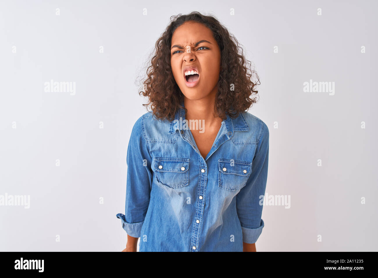 Young brazilian woman wearing denim shirt standing over isolated white ...