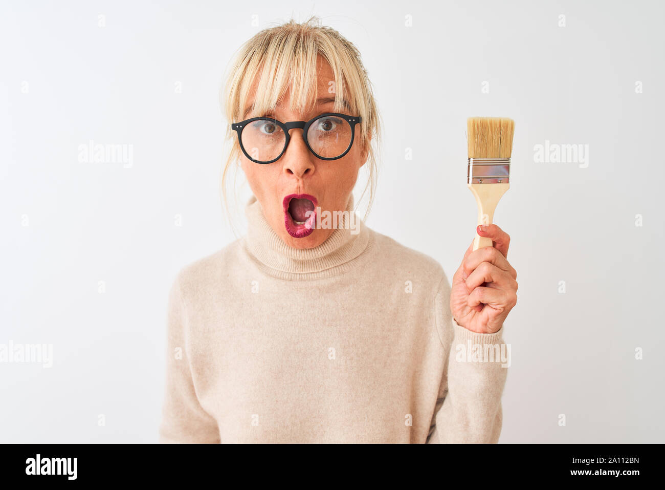 Middle age painter woman holding paint brush standing over isolated ...