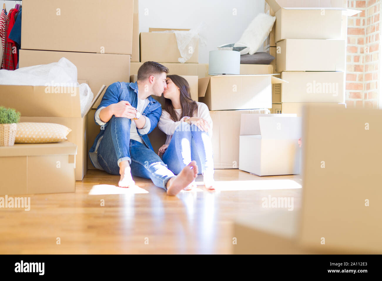 Young beautiful couple relaxing sitting on the floor around cardboard ...