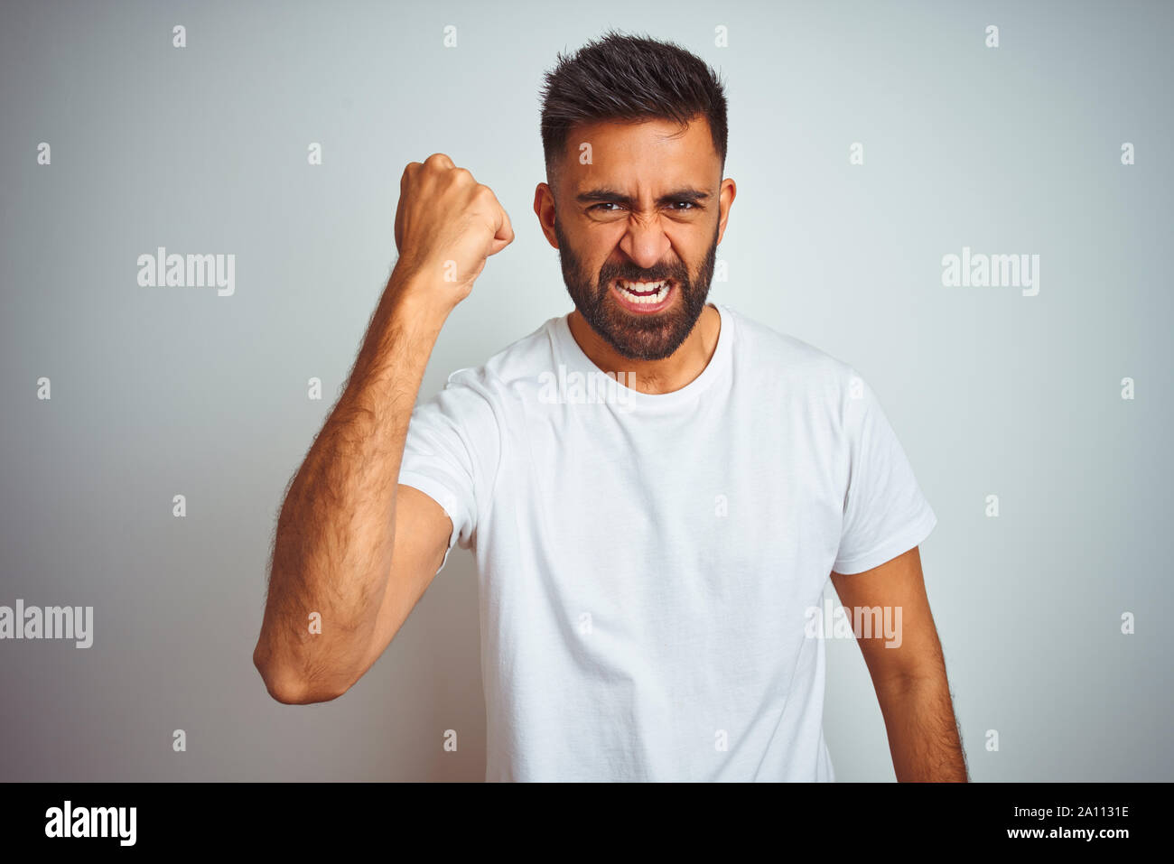 Young indian man wearing t-shirt standing over isolated white ...