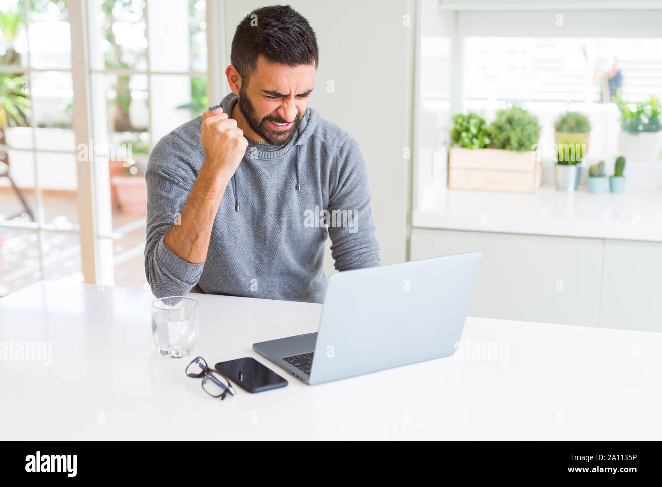 Handsome hispanic man working using computer laptop annoyed and ...