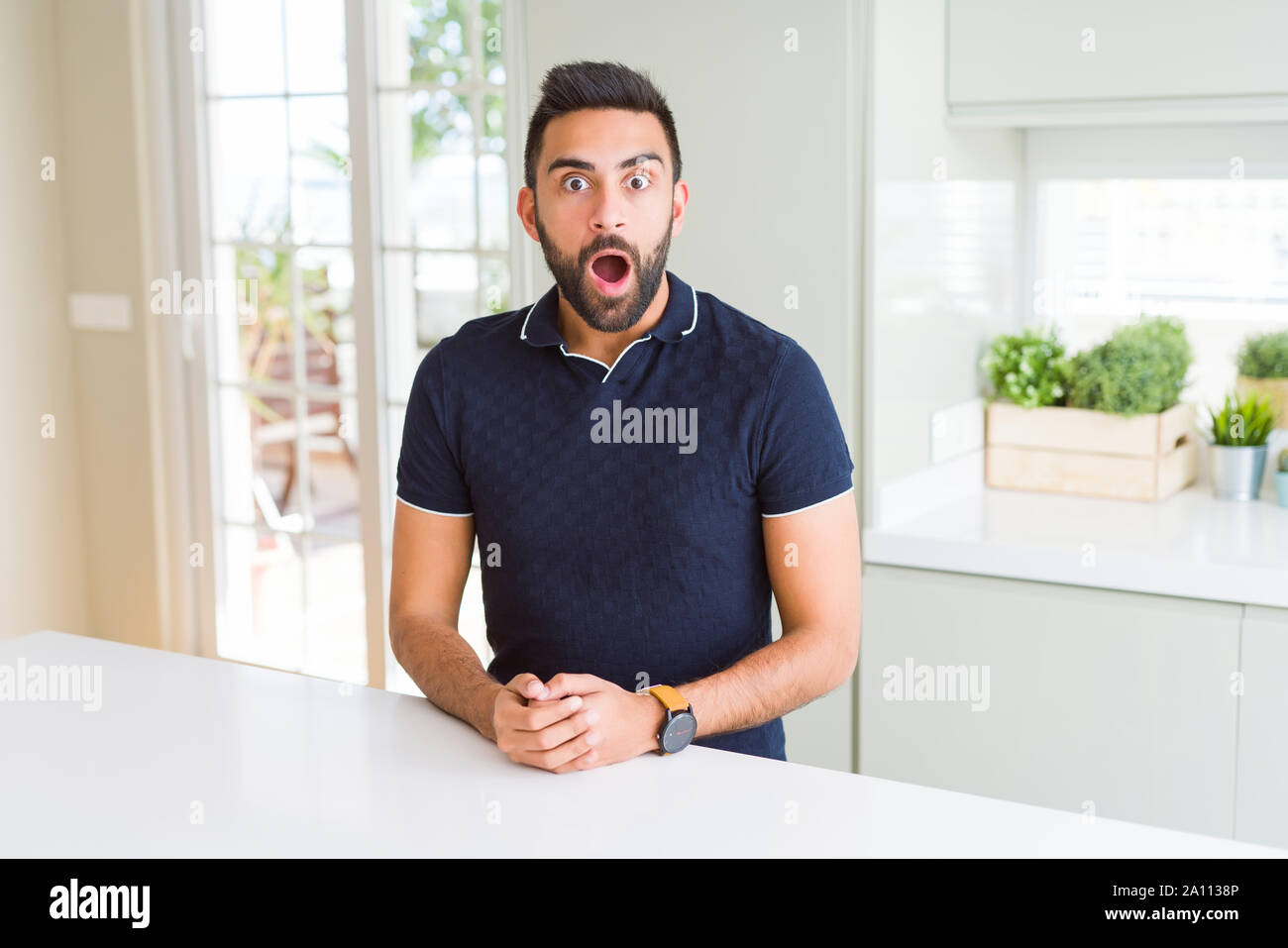 Handsome hispanic man at home afraid and shocked with surprise ...