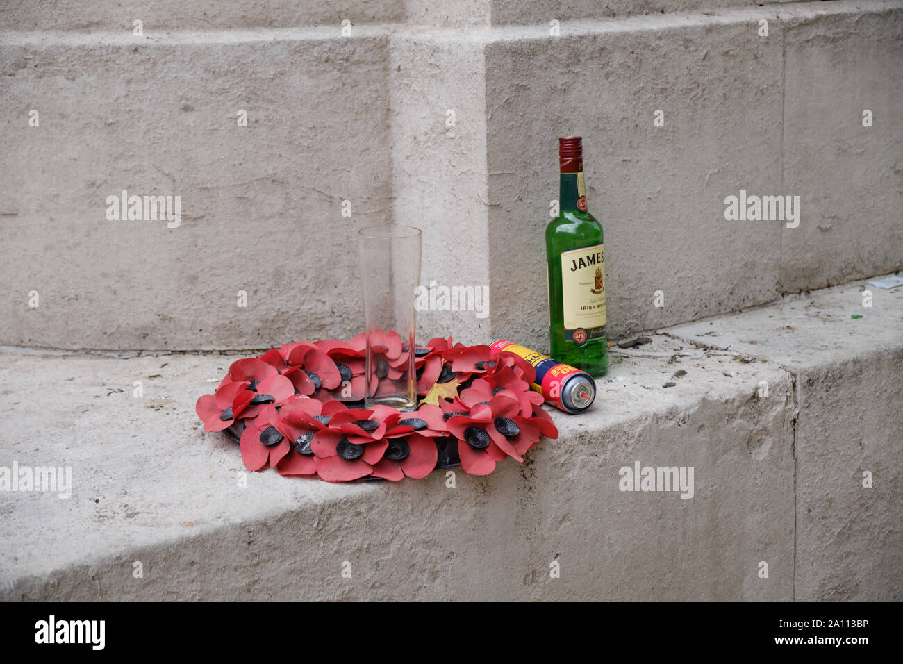 Empty bottle of whiskies and glass left abandoned by a plastic poppy ...