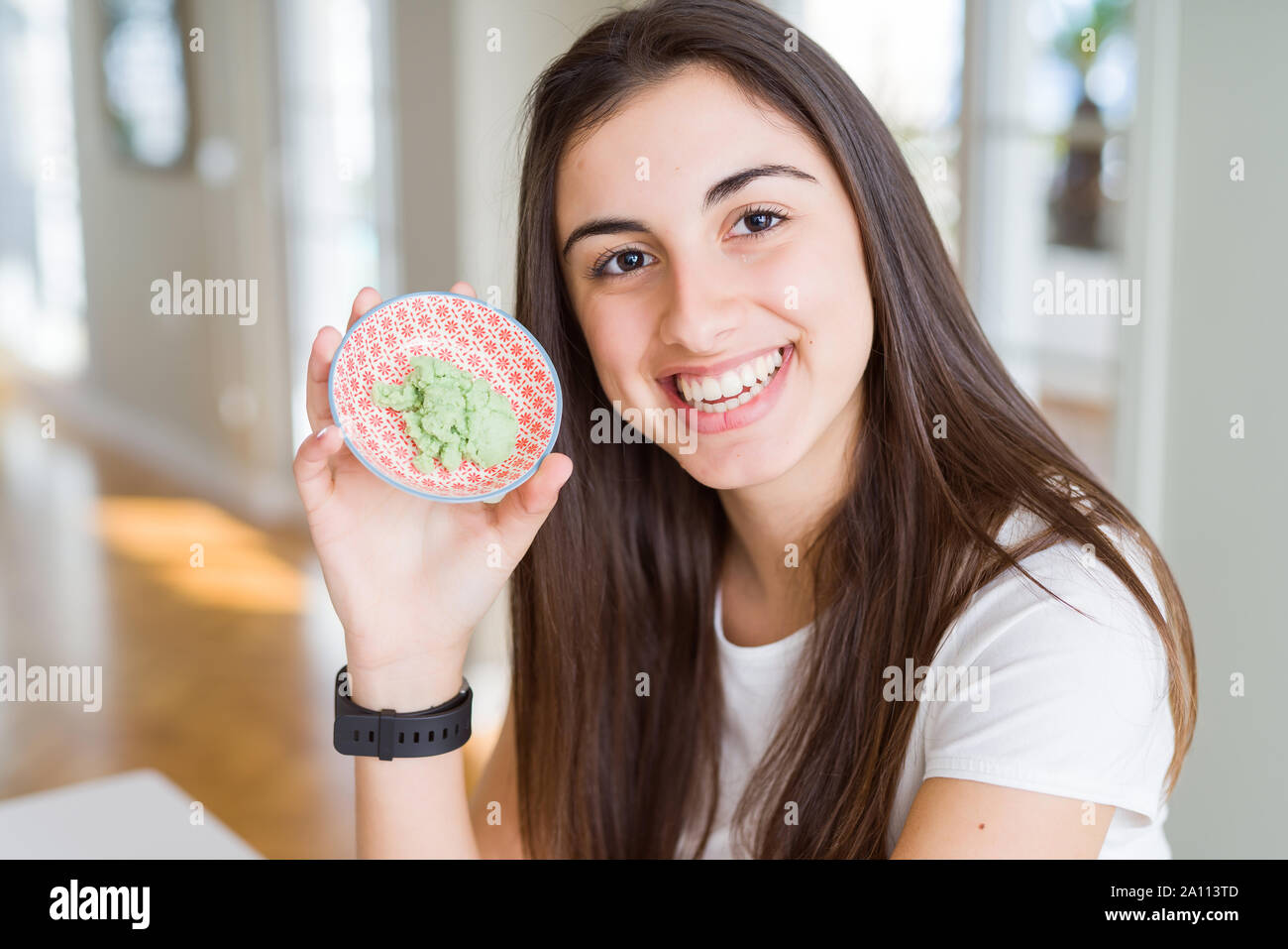 Beautiful young woman holding spicy asian wasabi with a happy face ...