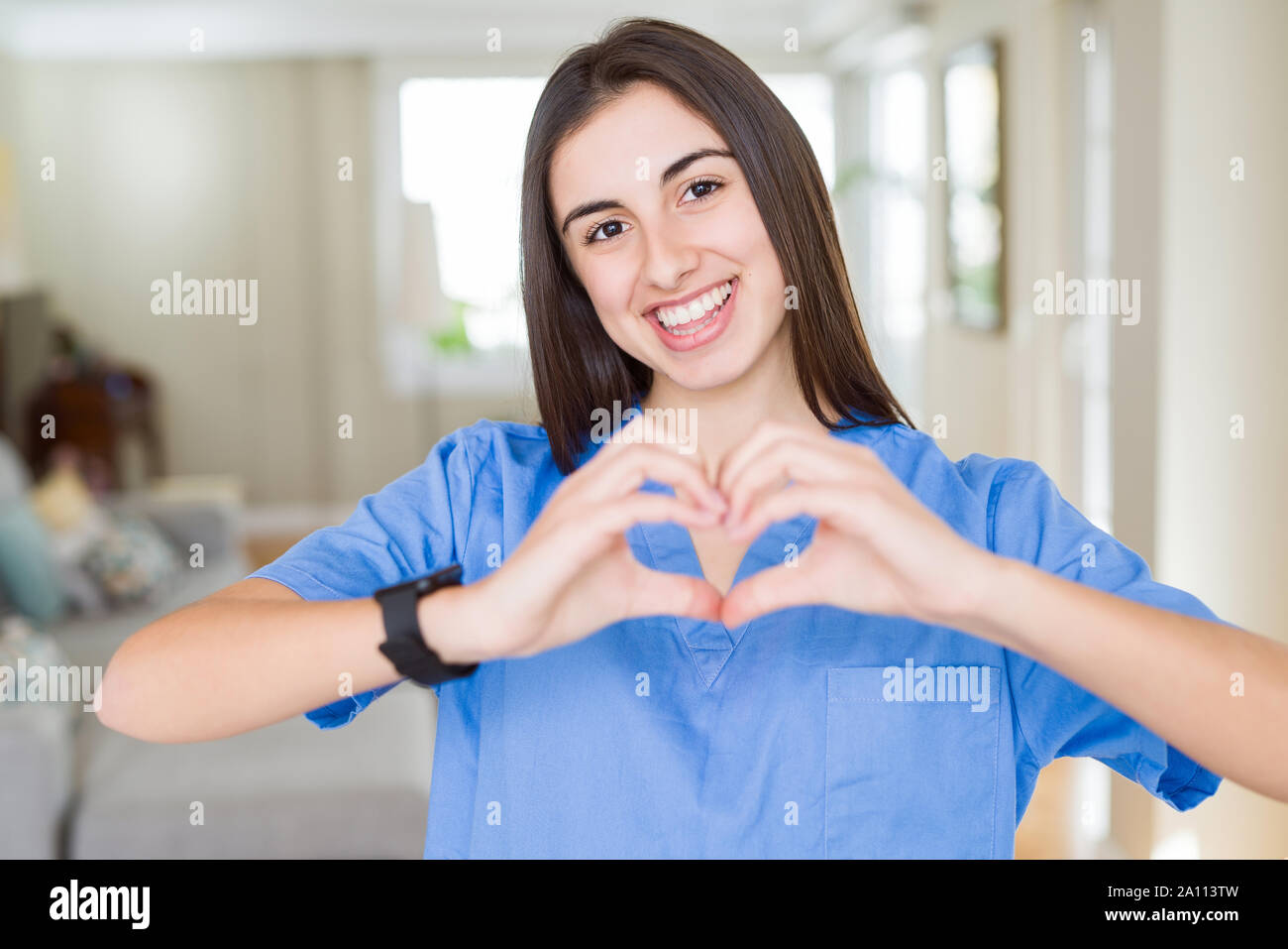 Beautiful young nurse woman at the clinic smiling in love showing heart ...