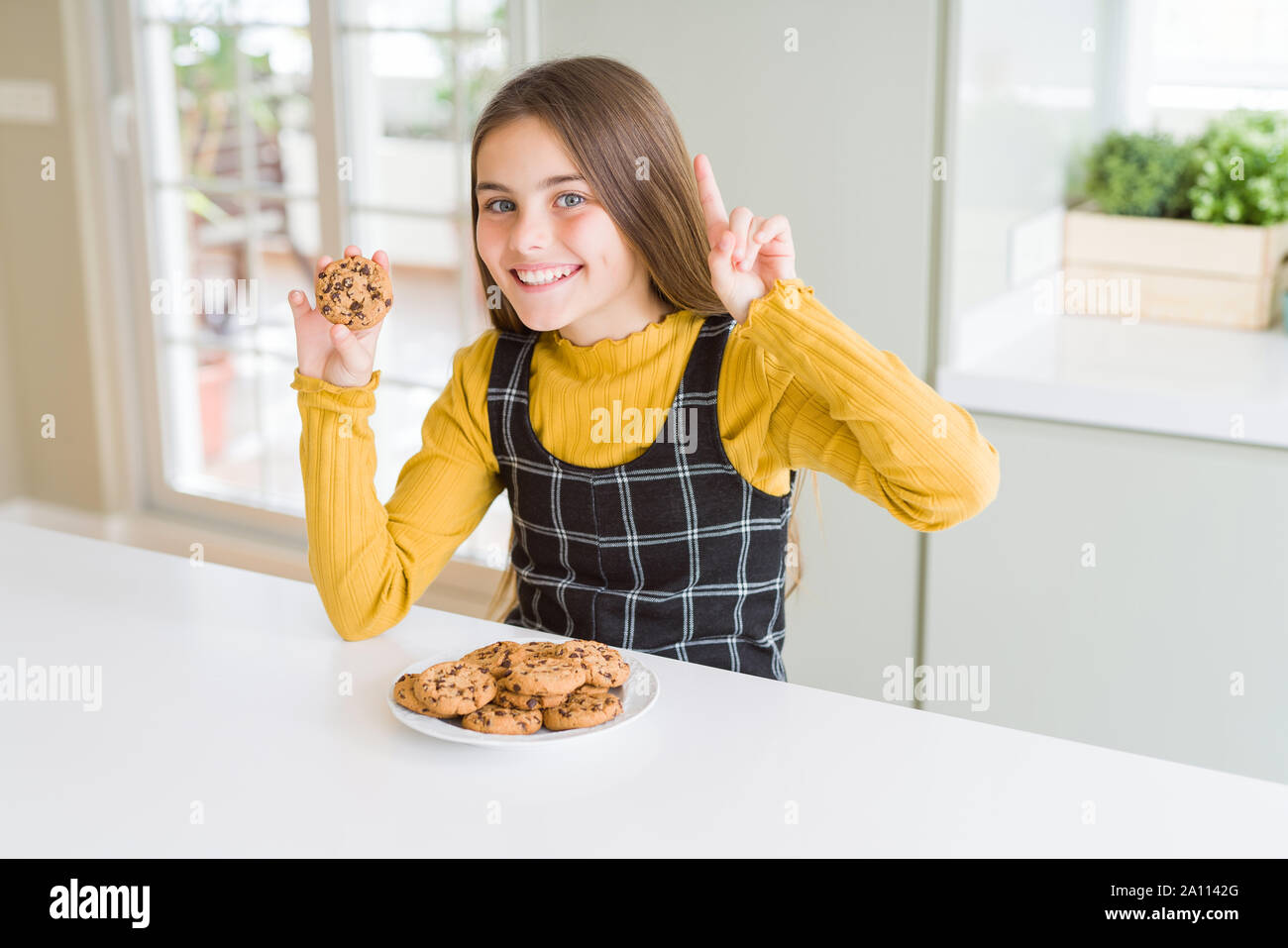 Beautiful young girl kid eating chocolate chips cookies surprised with ...