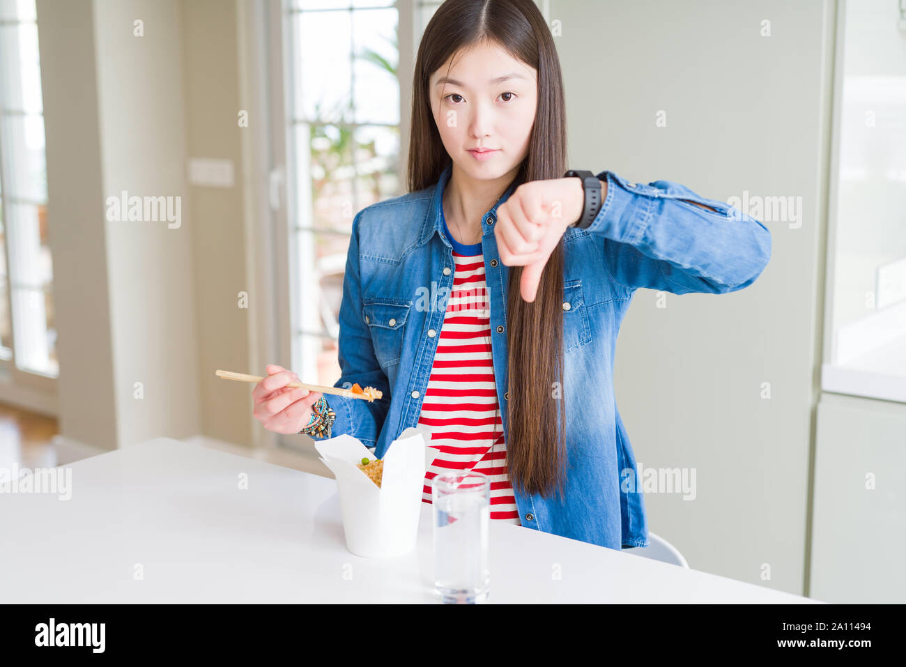 Beautiful Asian woman eating asian rice in delivery box with angry face ...